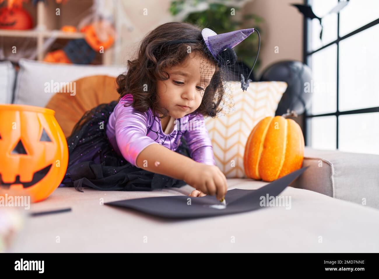 Adorable hispanic toddler having halloween party drawing on paper at ...