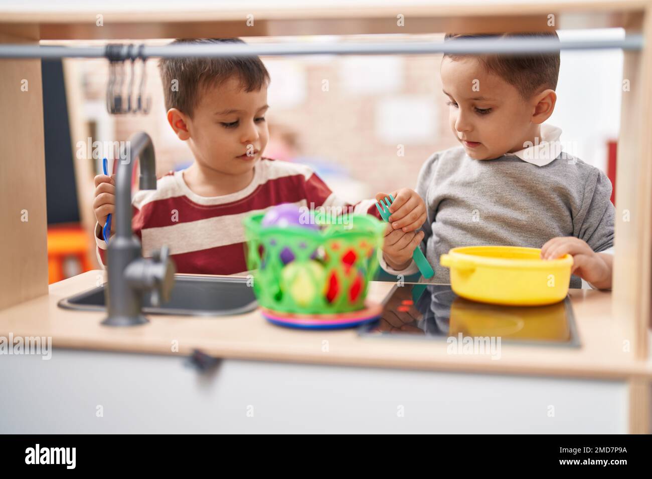 Two kids playing with play kitchen standing at kindergarten Stock Photo ...