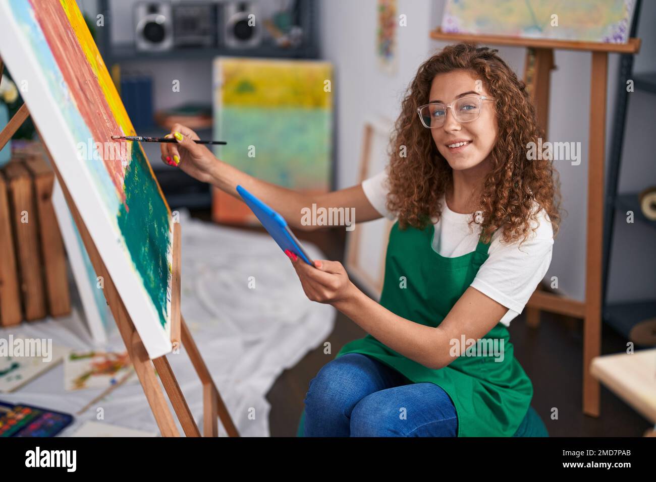 Young beautiful hispanic woman artist using touchpad drawing at art ...