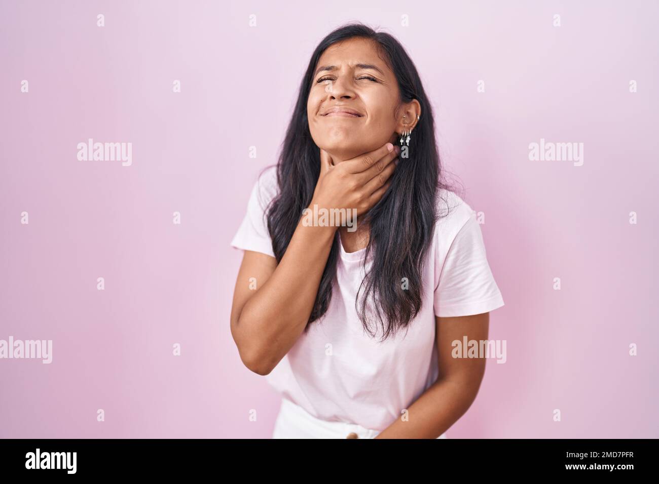 Young hispanic woman standing over pink background touching painful ...