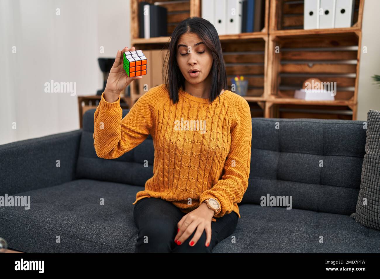 Young hispanic woman playing colorful puzzle cube intelligence game ...