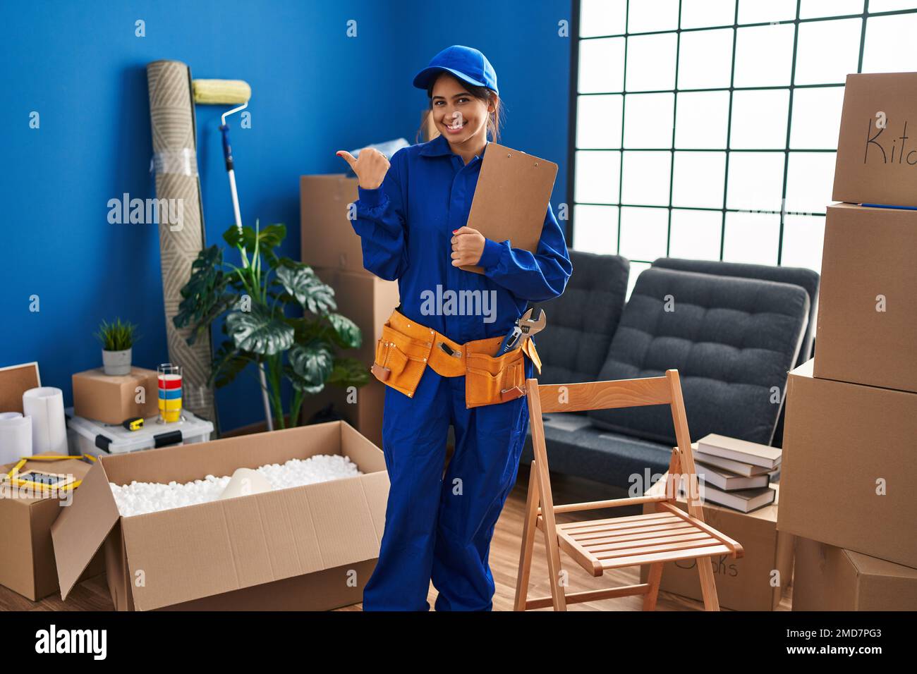 Young hispanic technician working at house renovation pointing thumb up ...