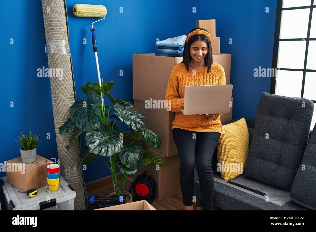 Young latin woman smiling confident using laptop at new home Stock ...