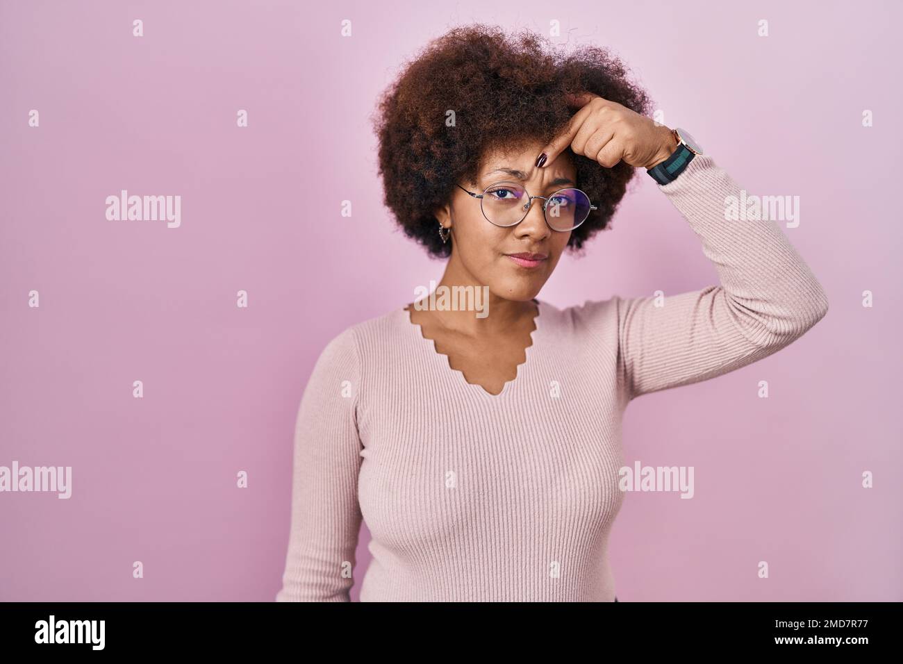 Young african american woman standing over pink background pointing ...