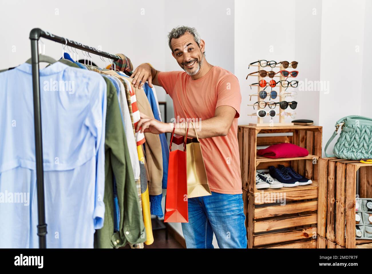 Middle age grey-haired man customer smiling confident holding clothes ...