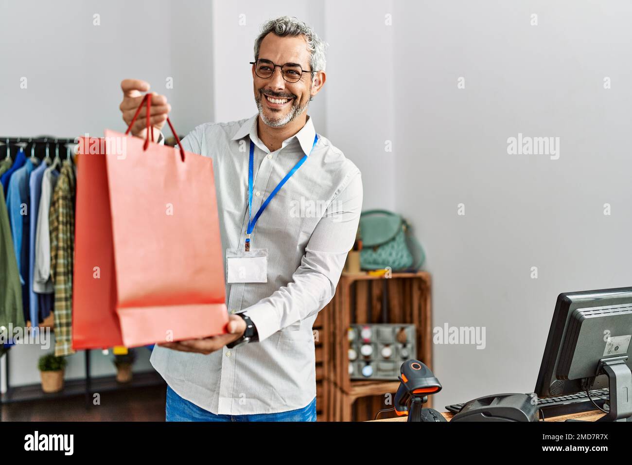 Middle age grey-haired man shop assistant holding shopping bag at ...