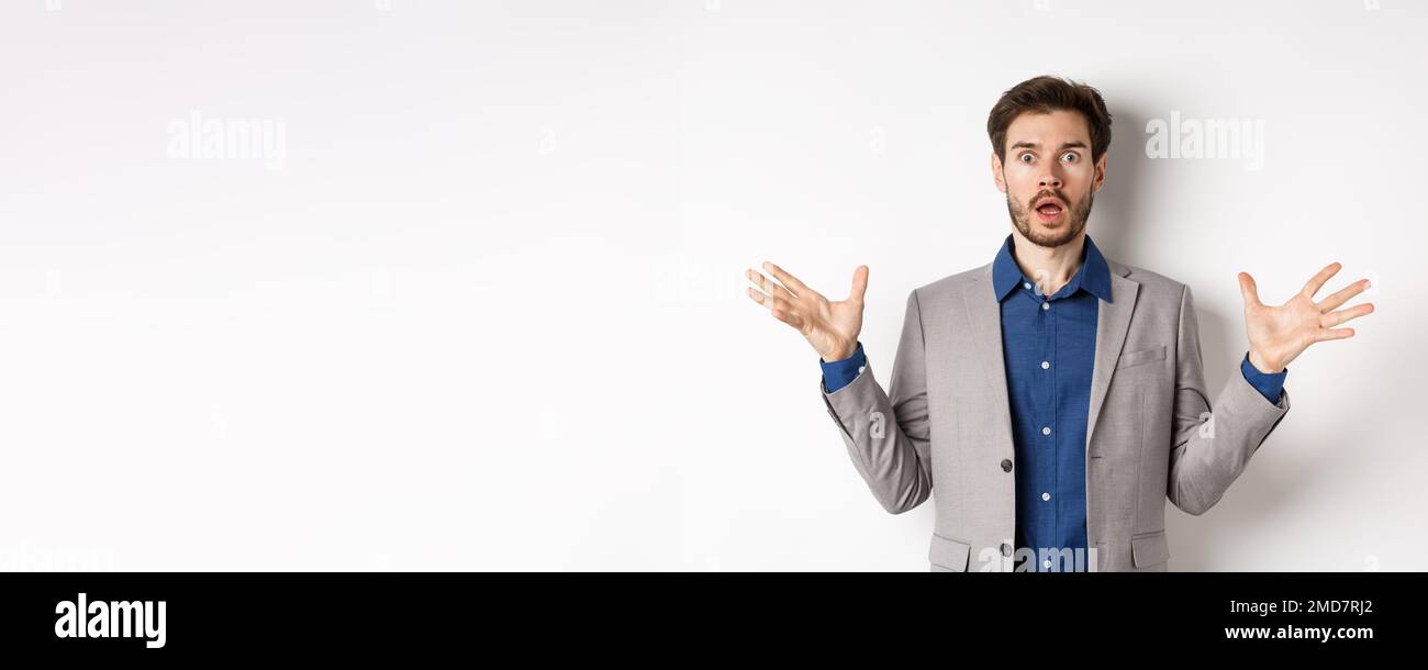 Shocked bearded guy in jacket spread hands sideways, gasping and ...