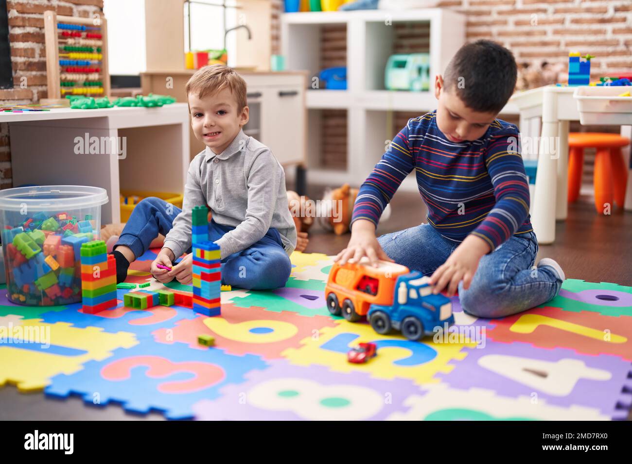 Two kids playing with construction blocks and truck toy sitting on ...