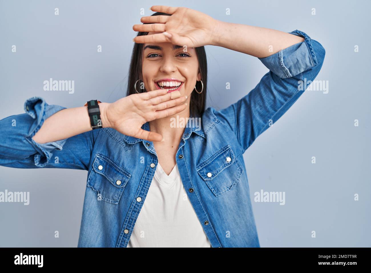 Hispanic woman standing over blue background smiling cheerful playing ...