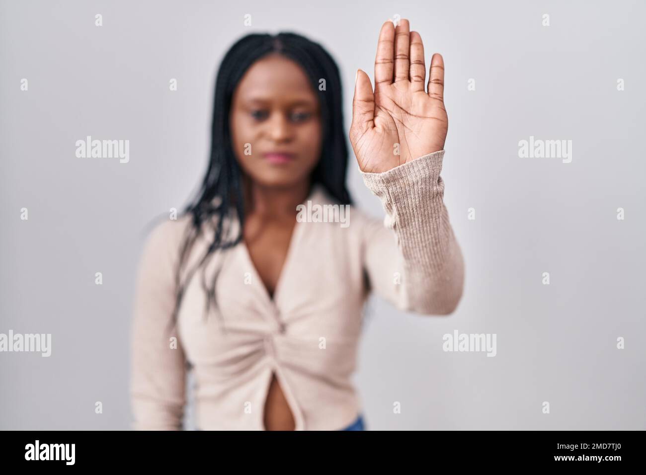 African woman with braids standing over white background doing stop ...