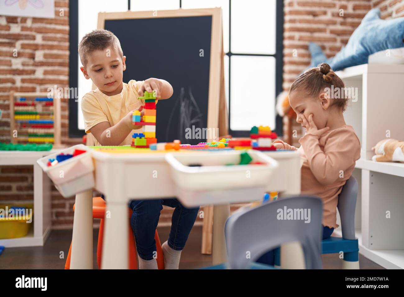 Two kids playing with construction blocks sitting on table at ...