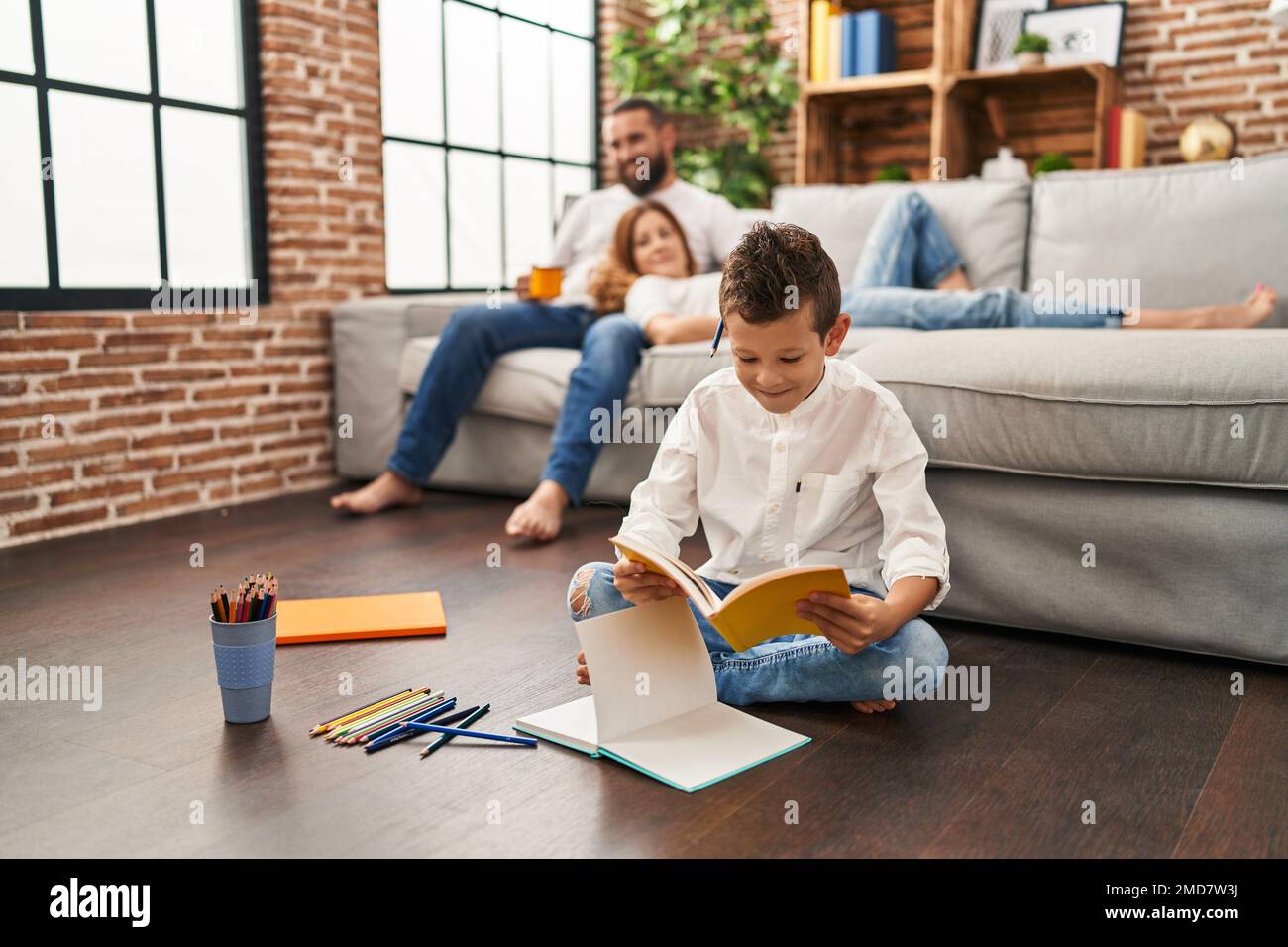 Family watching tv and son reading book at home Stock Photo - Alamy