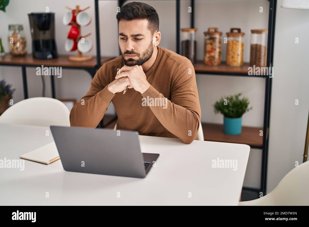 Young hispanic man using laptop sitting on table at home Stock Photo ...