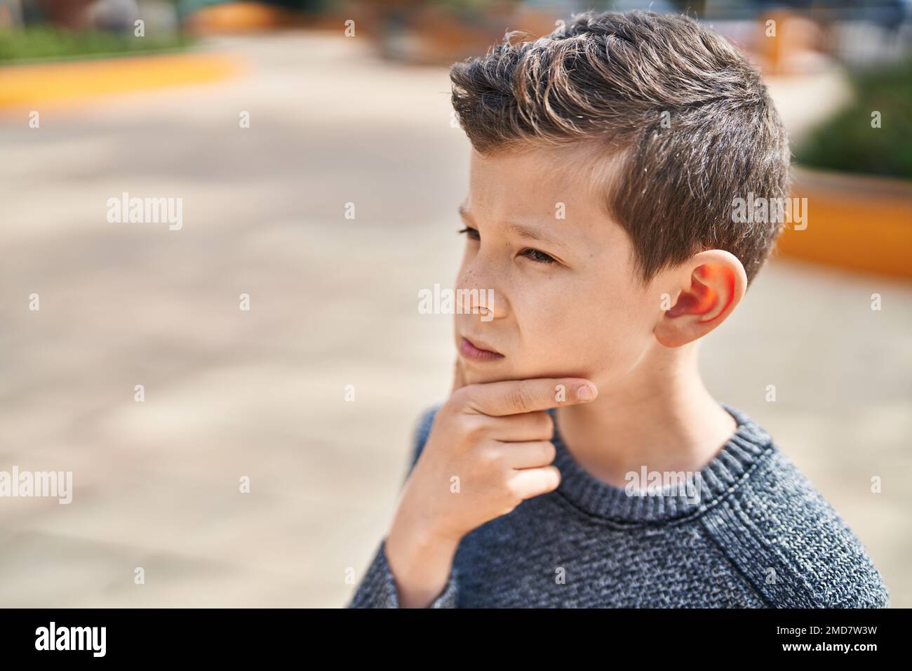 Blond child standing with doubt expression at park Stock Photo - Alamy