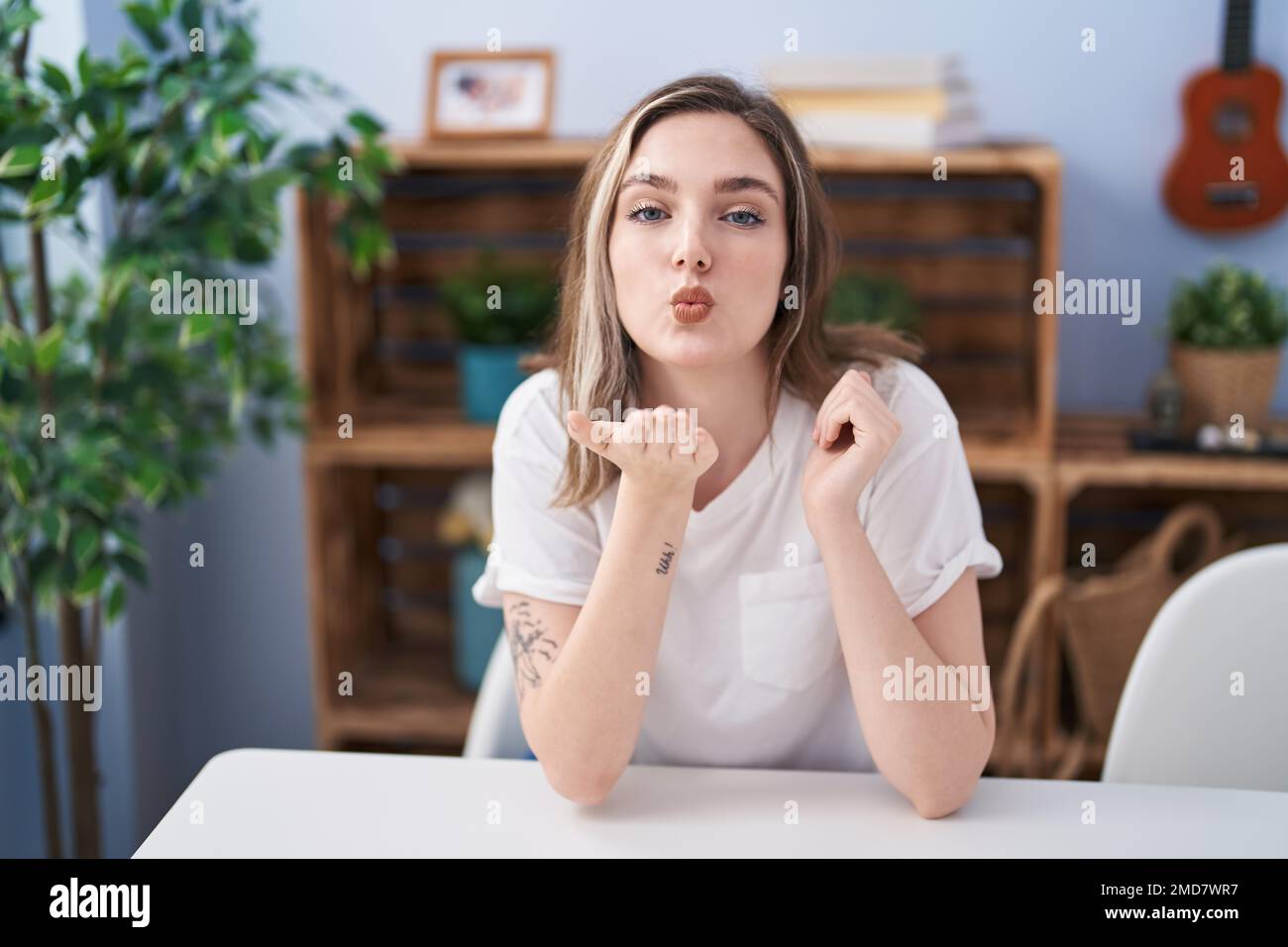 Young woman sitting on table kissing at home Stock Photo - Alamy