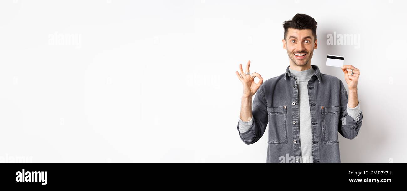 Very good. Smiling guy with plastic credit card showing okay sign ...