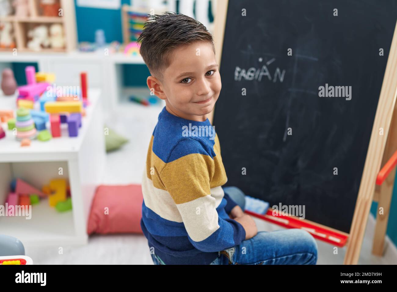 Adorable hispanic boy preschool student drawing on blackboard at ...