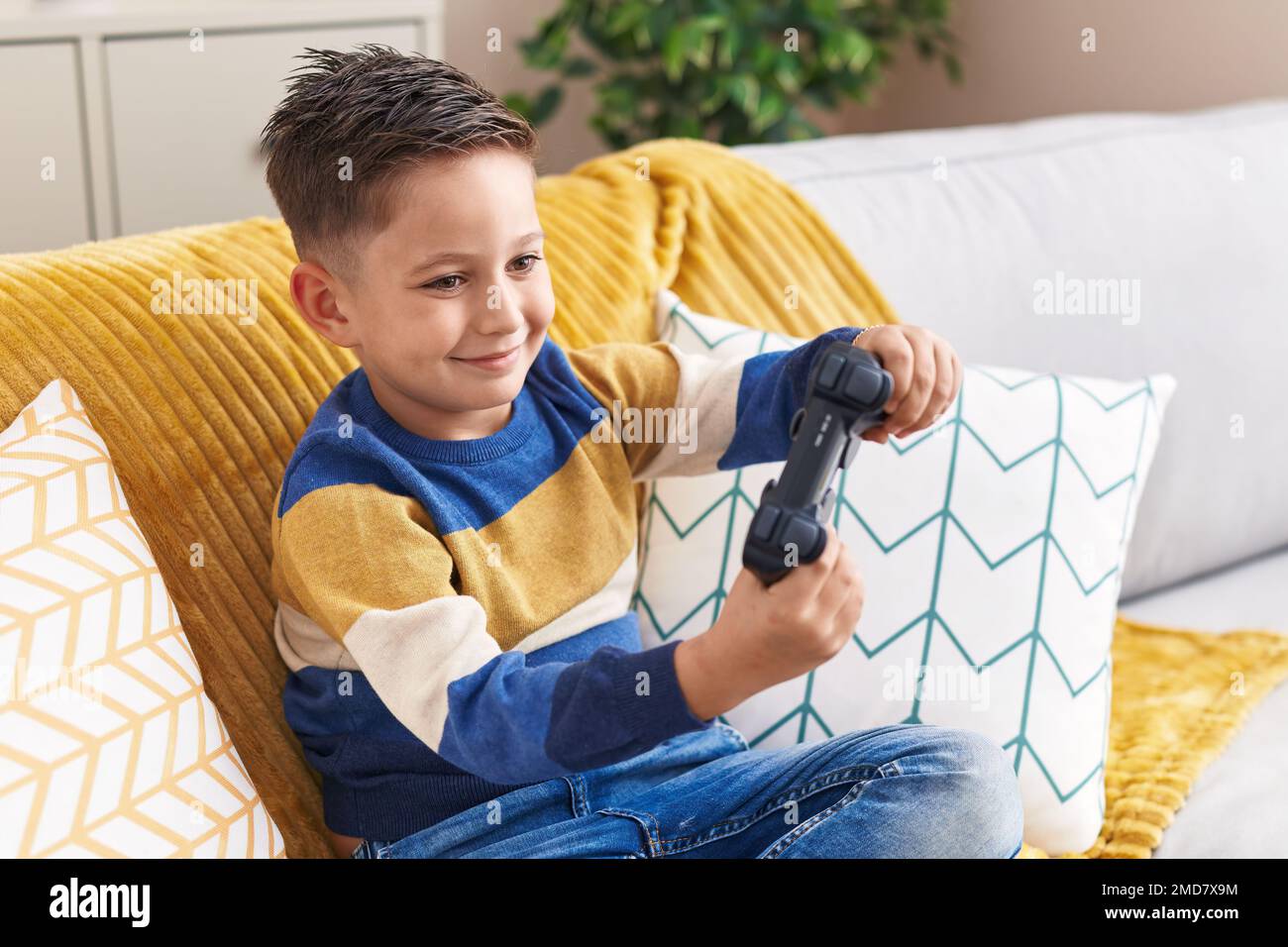 Adorable hispanic boy playing video game sitting on sofa at home Stock ...