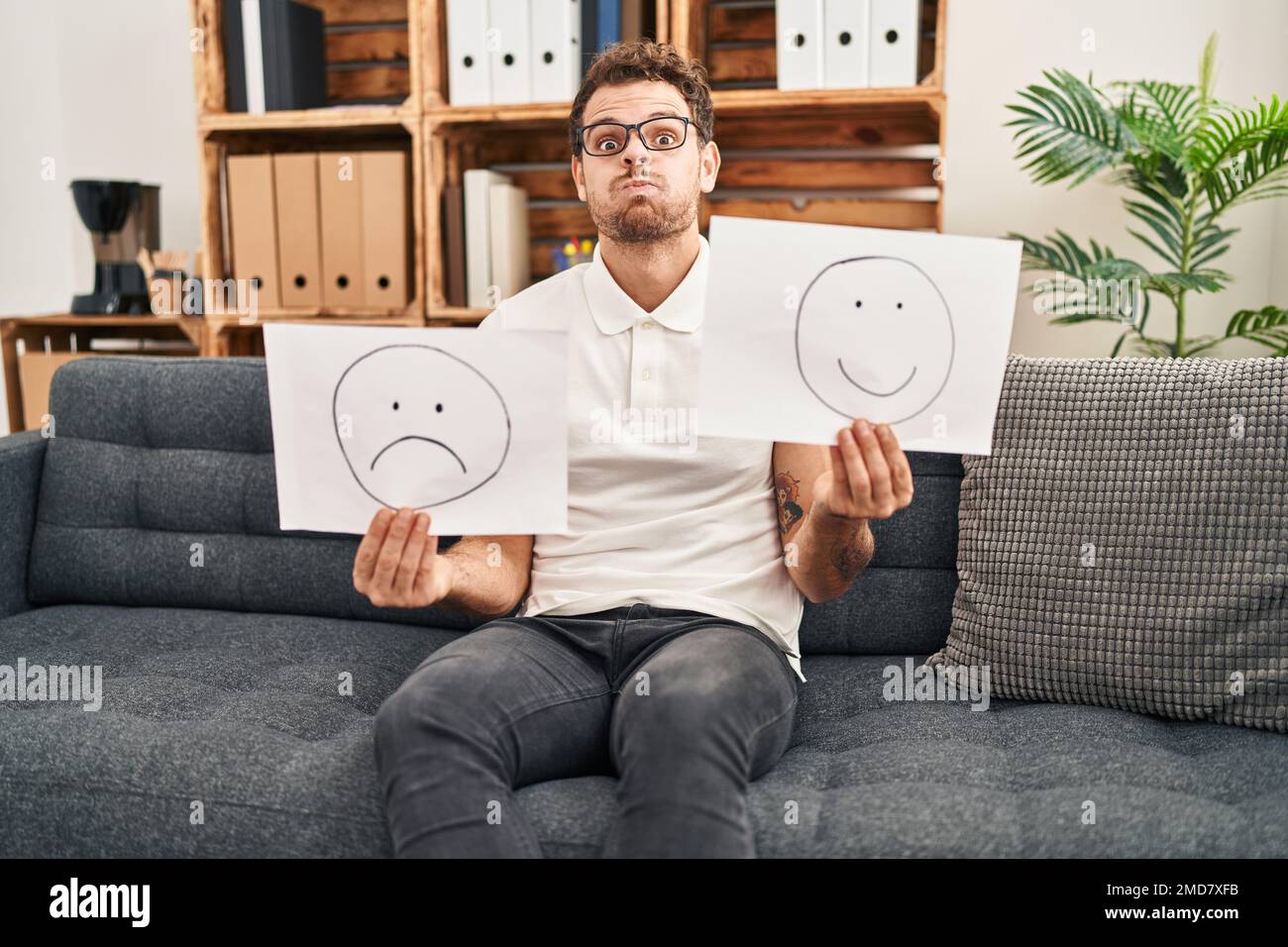Young hispanic man working on depression holding sad to happy emotion ...