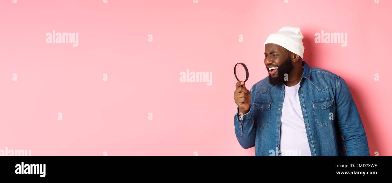 Confused Black man looking through magnifying glass at something ...