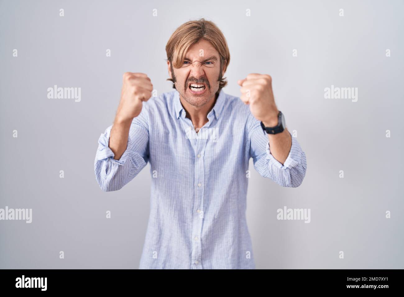 Caucasian man with mustache standing over white background angry and ...
