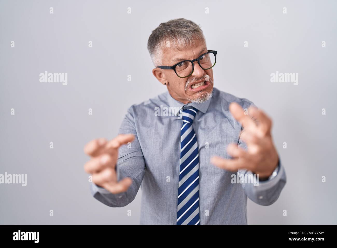 Hispanic business man with grey hair wearing glasses shouting ...