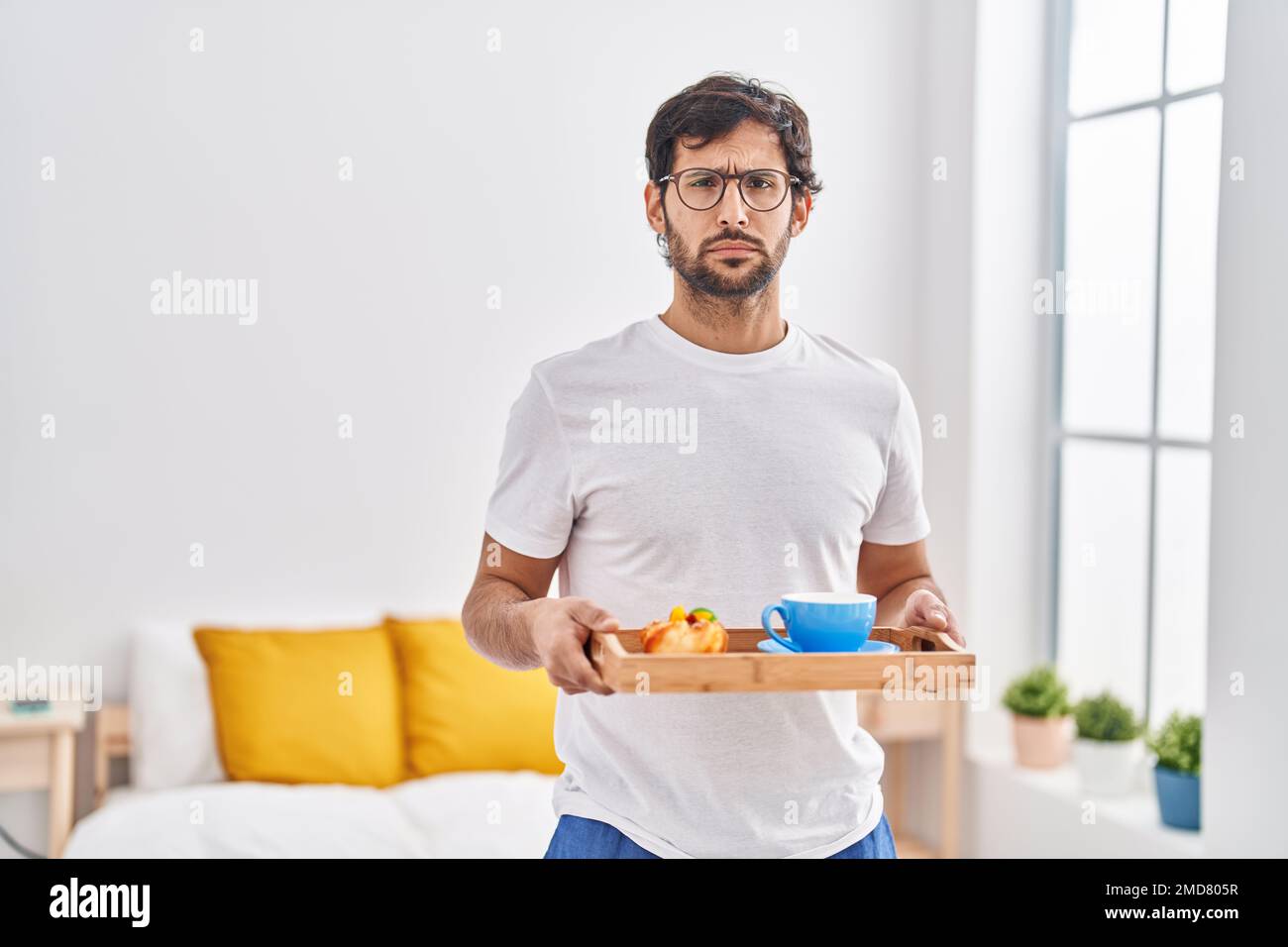 Handsome latin man eating breakfast on the bed depressed and worry for ...