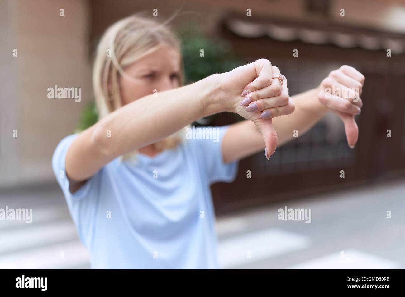 Young blonde woman doing negative sign with thumbs down at coffee shop ...