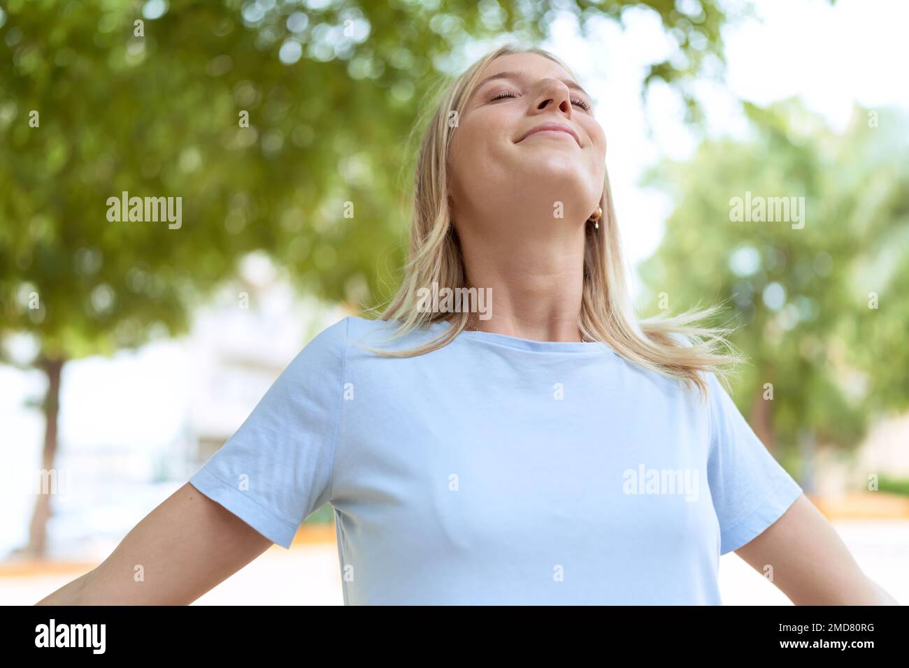 Young blonde woman breathing with arms open at park Stock Photo - Alamy