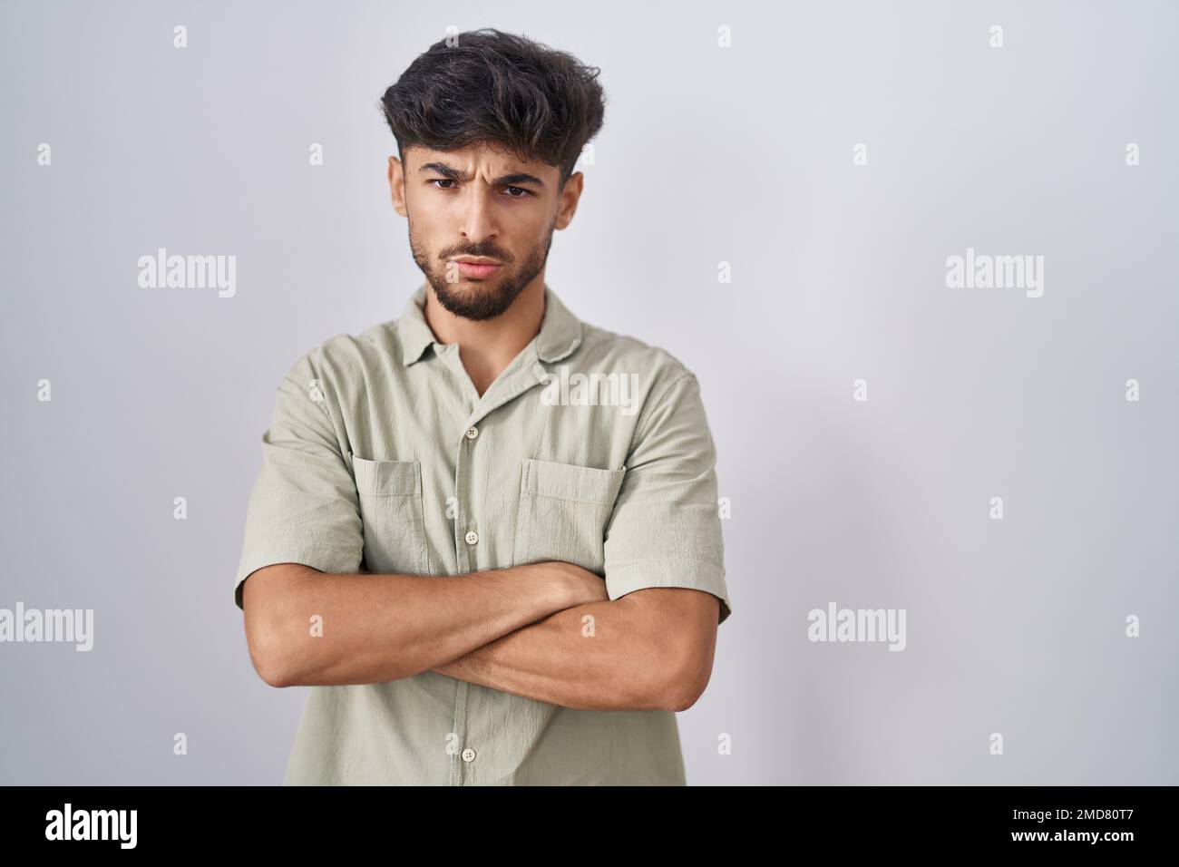 Arab man with beard standing over white background skeptic and nervous ...