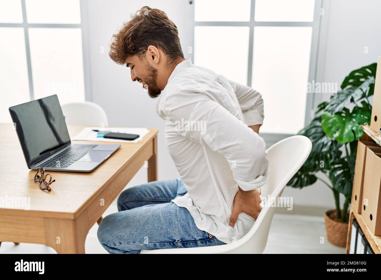 Young arab man suffering for back pain working at office Stock Photo ...