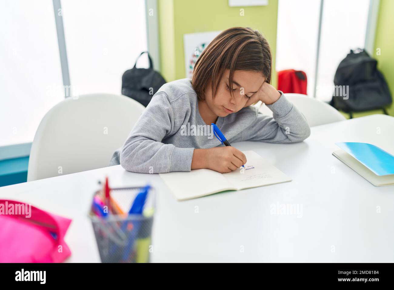 Adorable hispanic boy student writing on notebook at classroom Stock ...