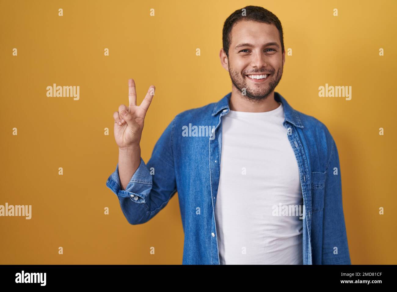 Hispanic man standing over yellow background showing and pointing up ...