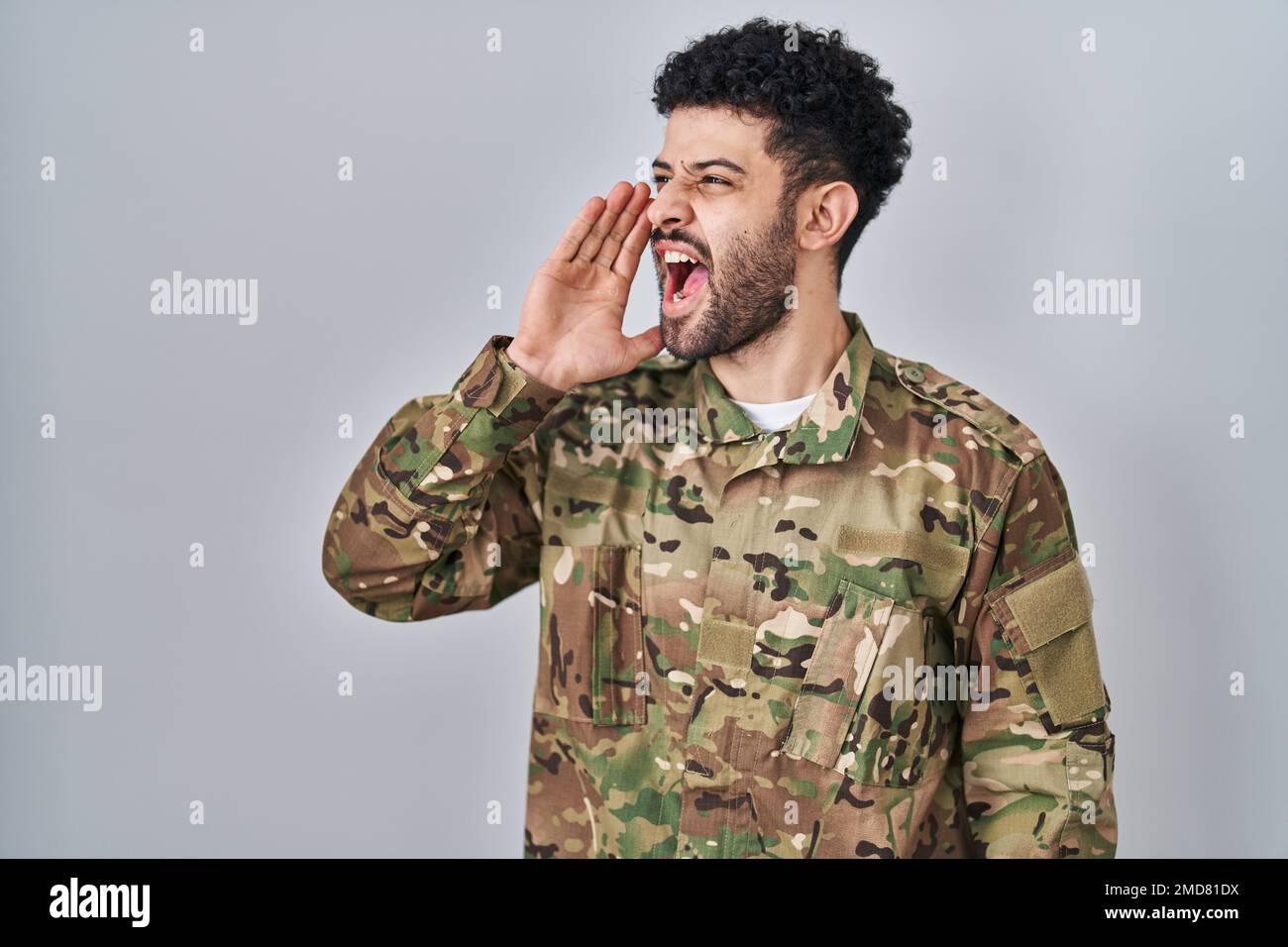 Arab man wearing camouflage army uniform shouting and screaming loud to ...