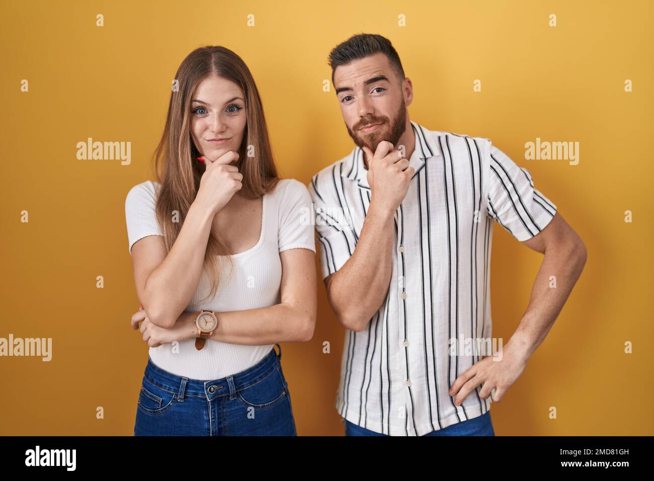 Young couple standing over yellow background looking confident at the ...