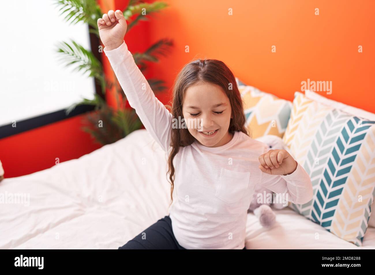 Adorable hispanic girl waking up stretching arms at bedroom Stock Photo ...