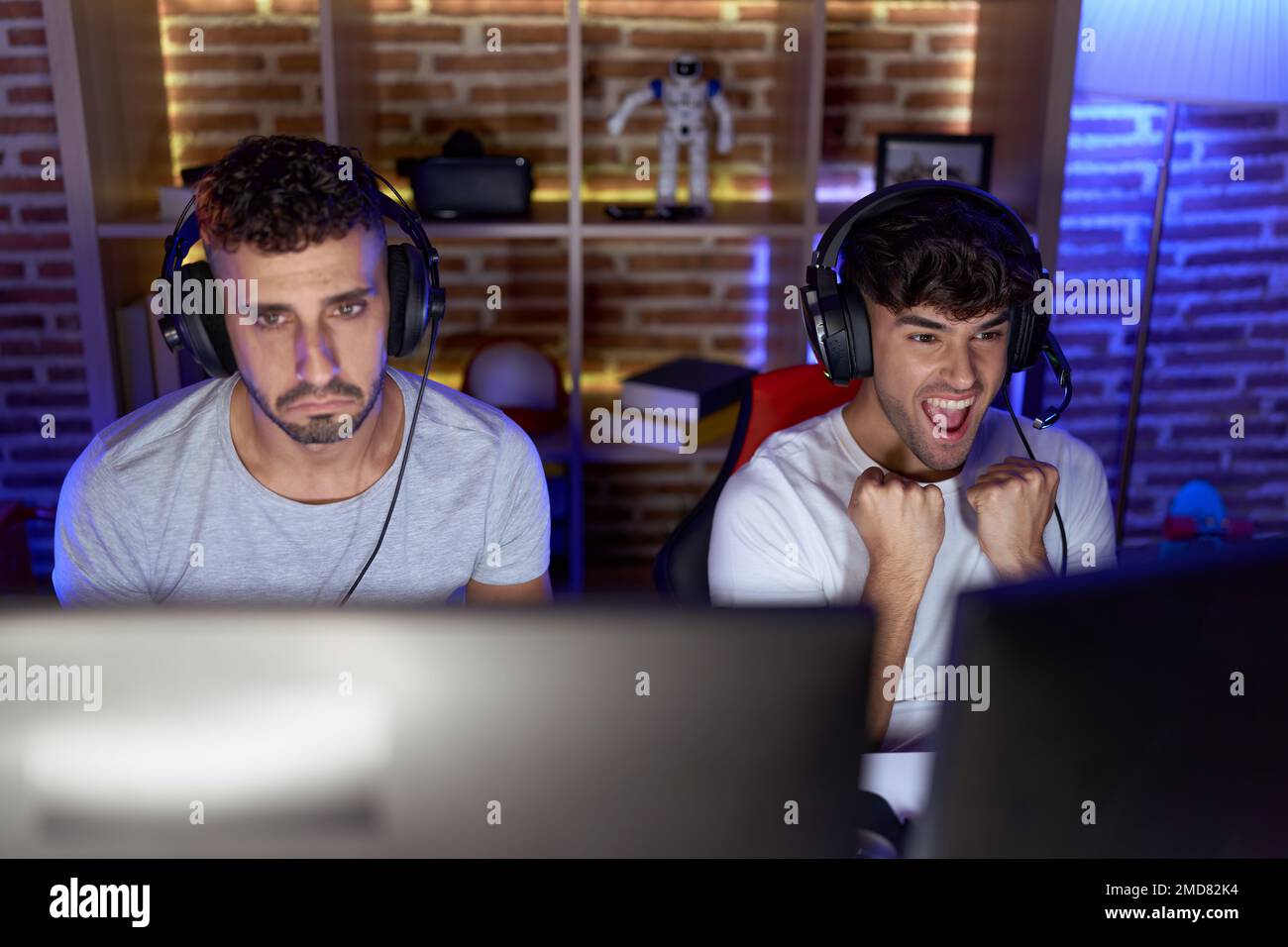 Two hispanic men streamers playing video game with winner expression at ...