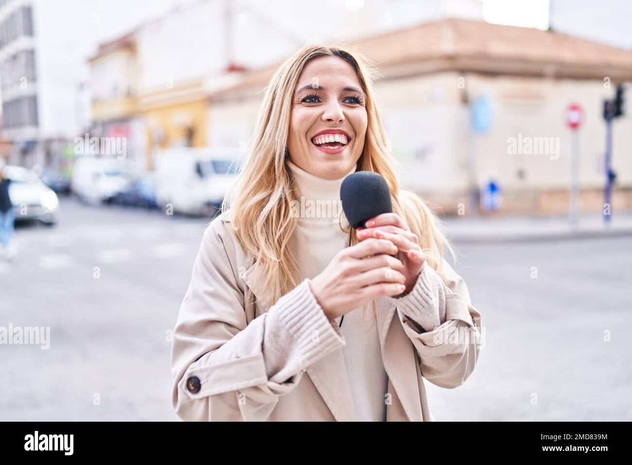 Young blonde woman reporter working using microphone at street Stock ...