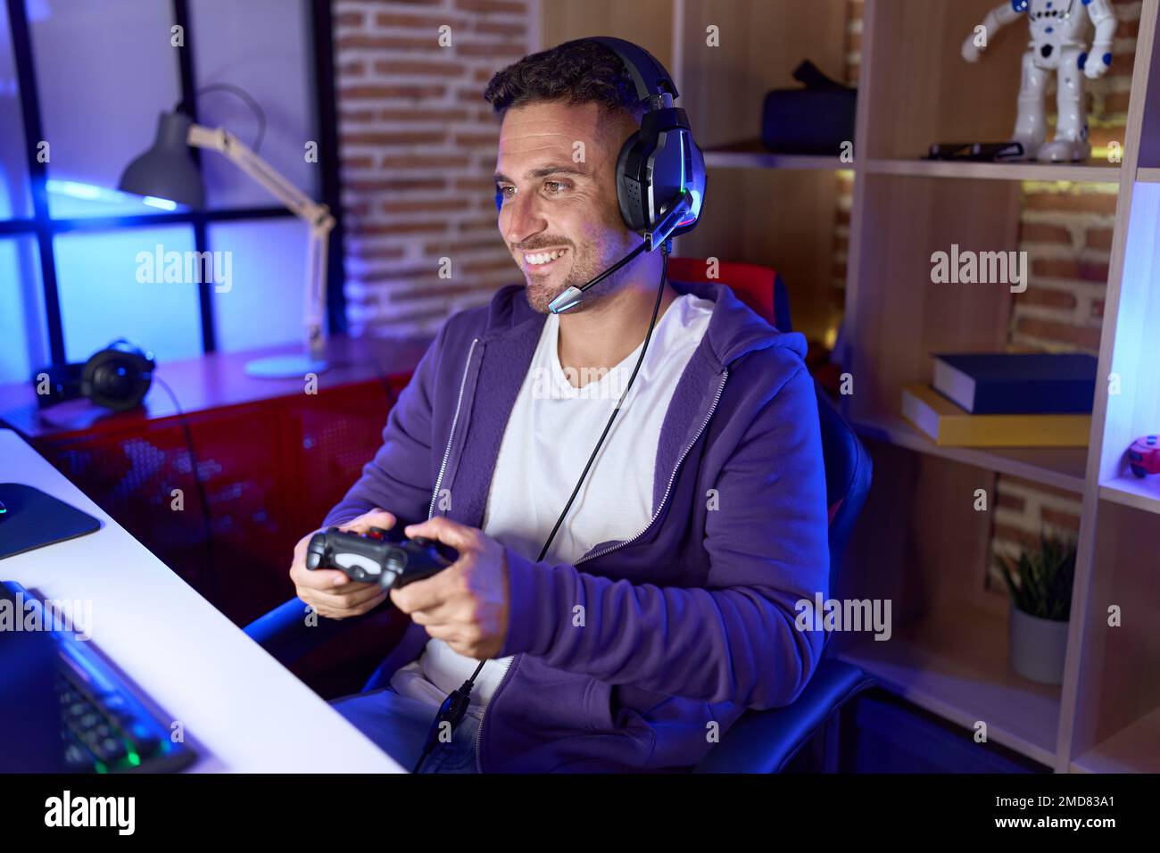 Young hispanic man streamer playing video game using joystick at gaming ...