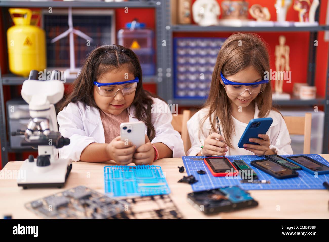 Two kids students using smartphones standing at laboratory classroom ...