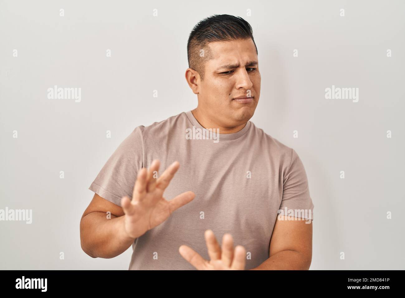 Hispanic young man standing over white background disgusted expression ...