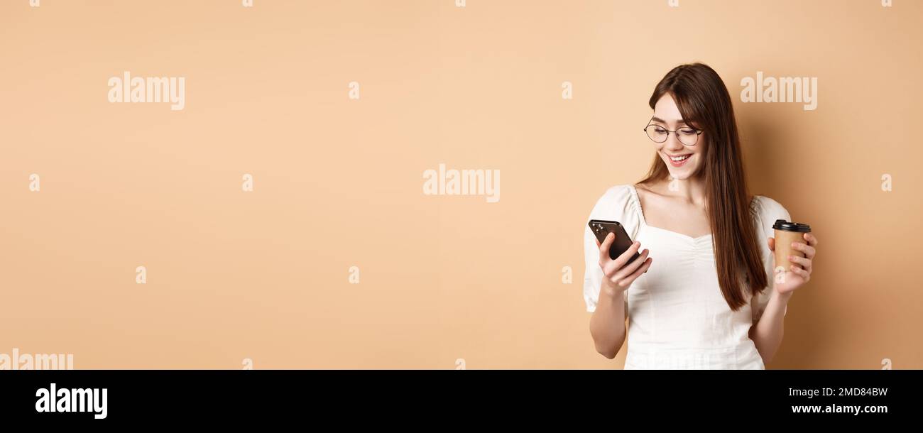 Happy girl chatting on phone and drinking coffee, wearing eyewear and ...