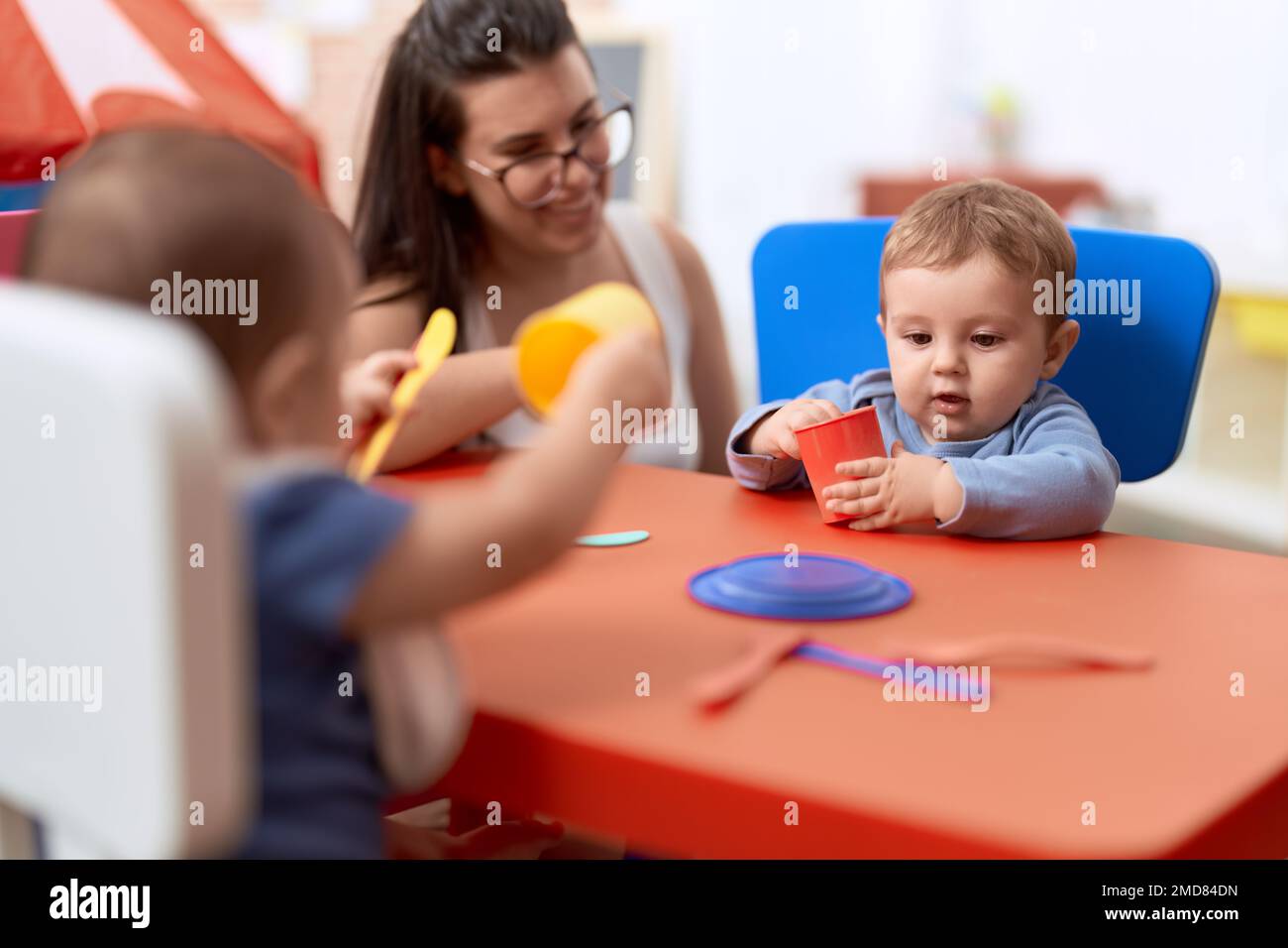 Teacher and preschool student sitting on table learning to eat at ...
