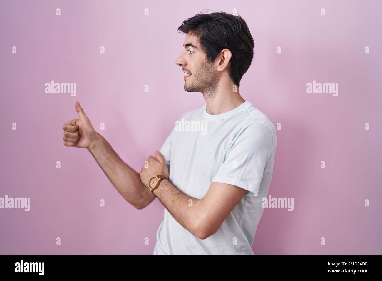 Young hispanic man standing over pink background looking proud, smiling ...