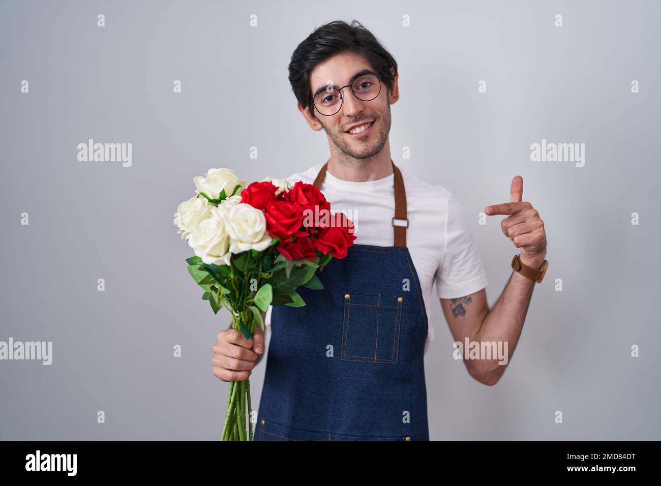 Young hispanic man holding bouquet of white and red roses looking ...