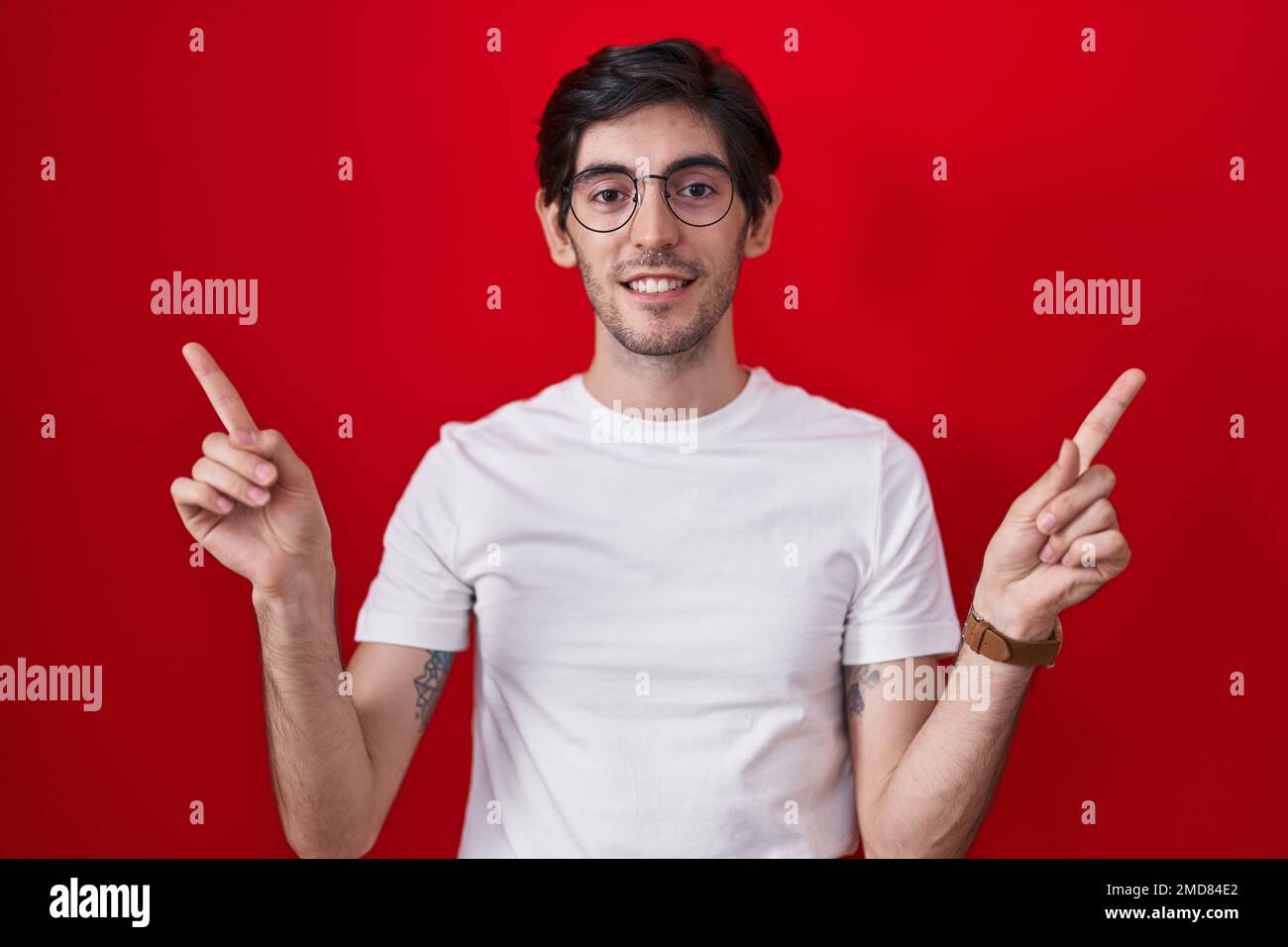 Young hispanic man standing over red background smiling confident ...