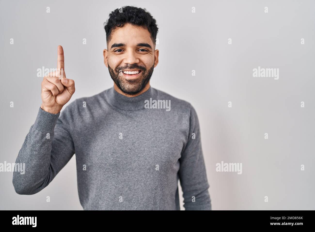 Hispanic man with beard standing over white background showing and ...