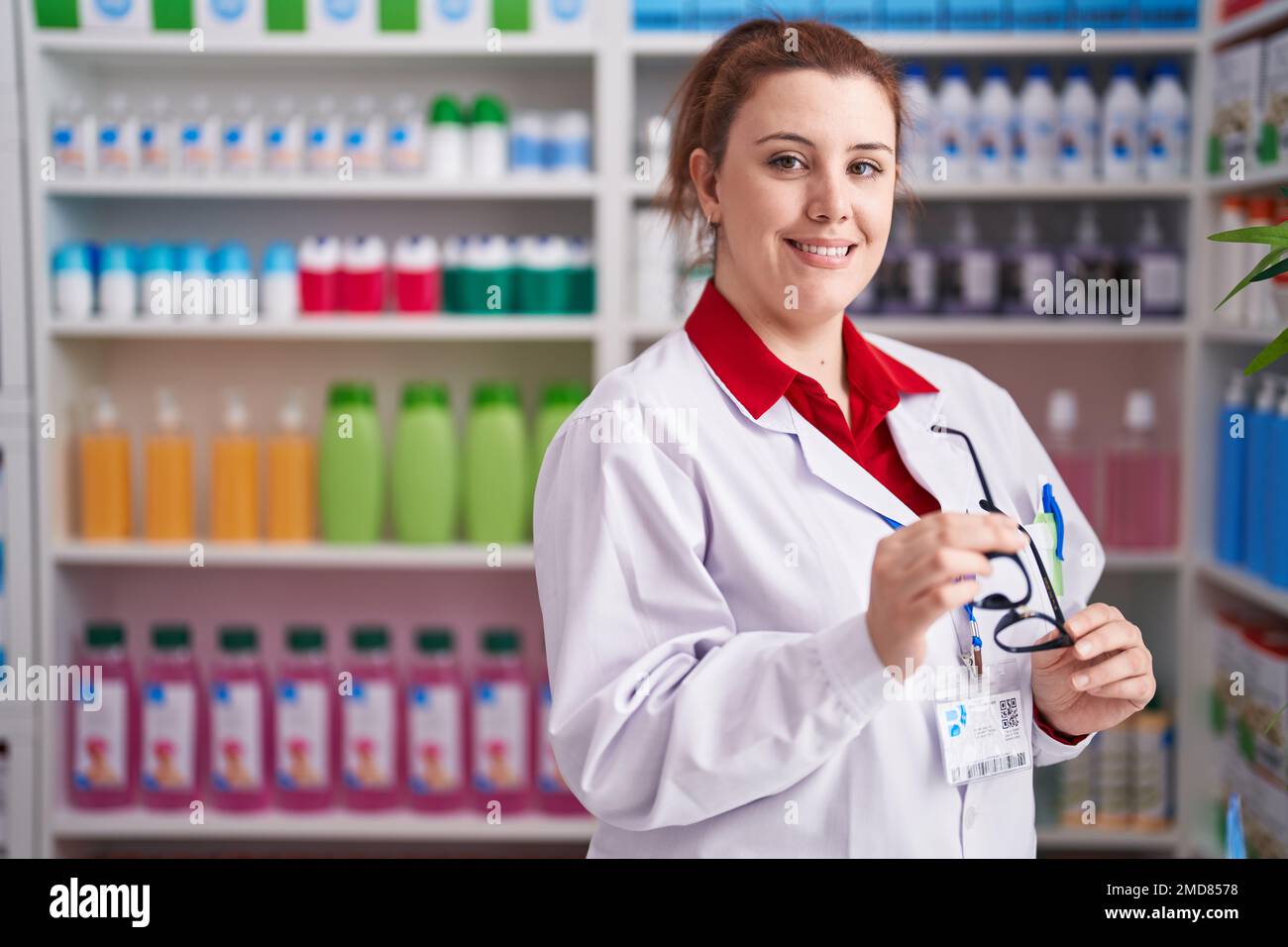 Young beautiful plus size woman pharmacist smiling confident holding ...