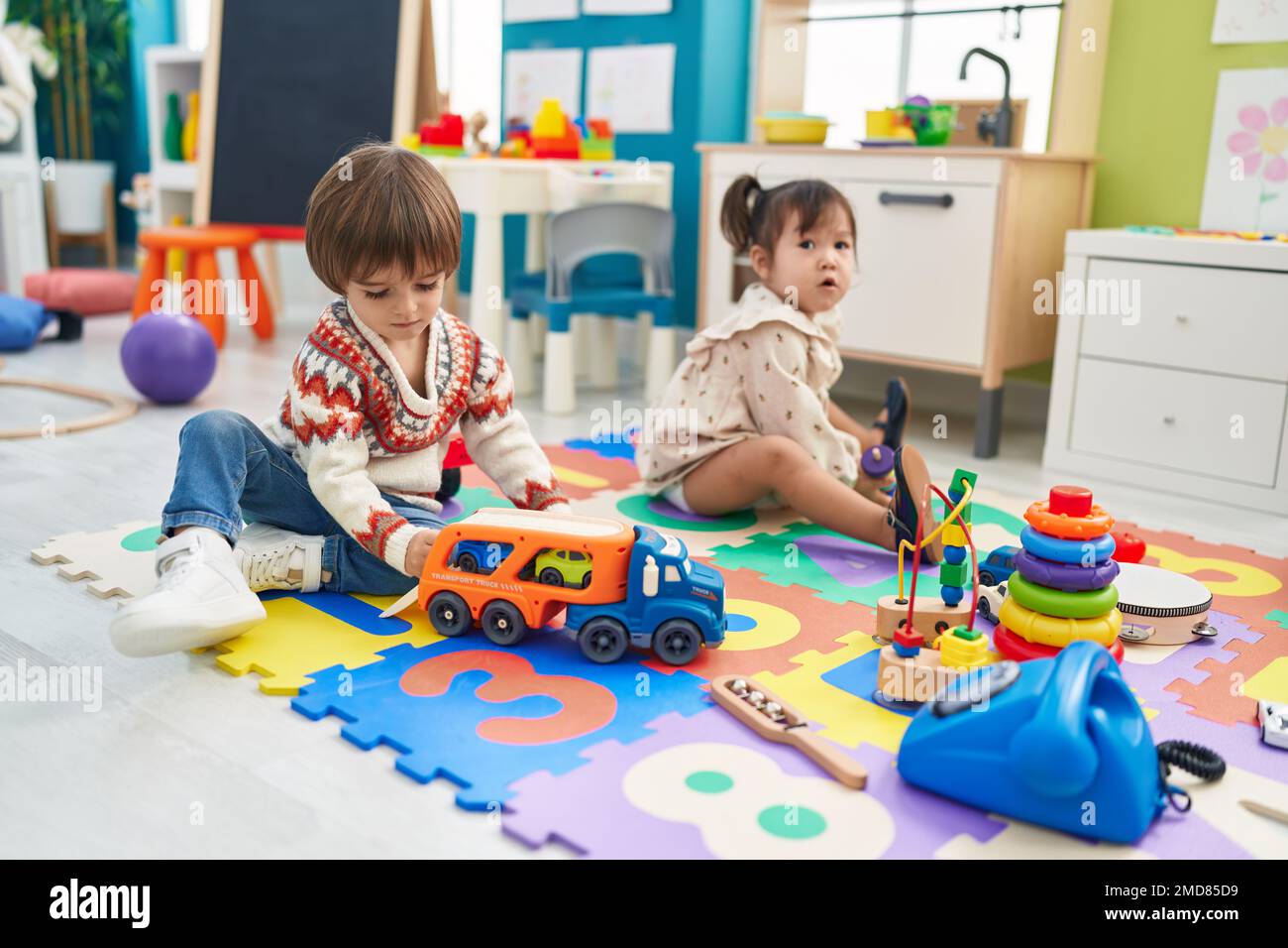Two kids playing with cars toy sitting on floor at kindergarten Stock ...