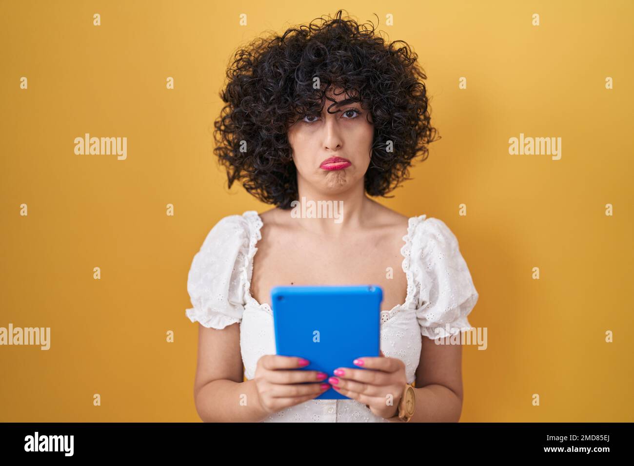 Young brunette woman with curly hair using touchpad over yellow ...